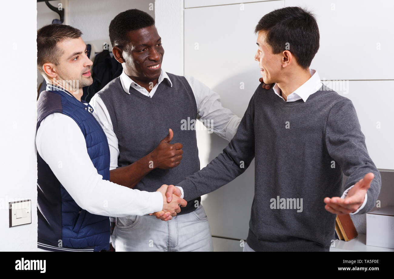 Adult male is welcoming his friends who visit him at home Stock Photo ...