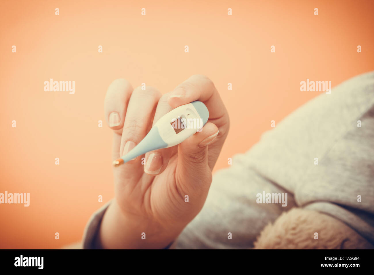 Closeup of sick ill human hand with digital thermometer. Young girl ...