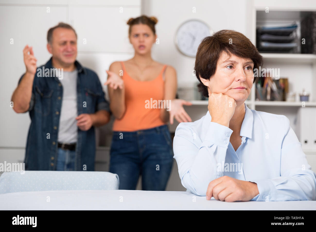 Upset mother is sitting at the table and her family is sympathying with ...