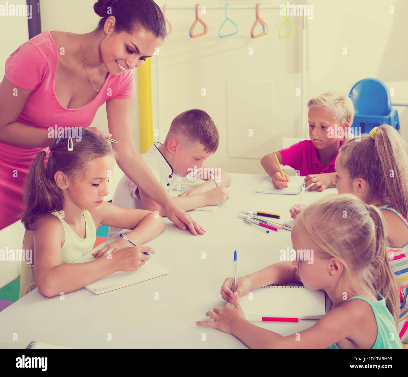 positive children making writing exercises with help of teacher in ...