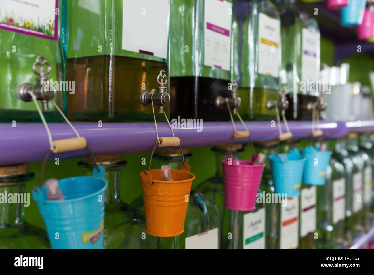 Image of colored pails hanging on taps of perfume bottles on shelves in ...