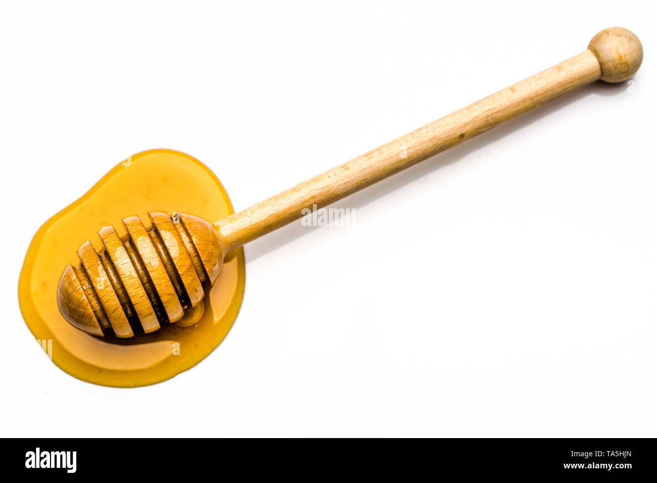 Drop of honey, top view with a wooden honey dipper isolated on white ...