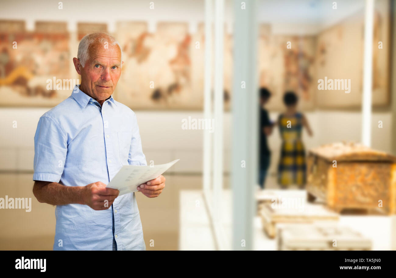 Senior man observing with interest exhibition under glass in art ...