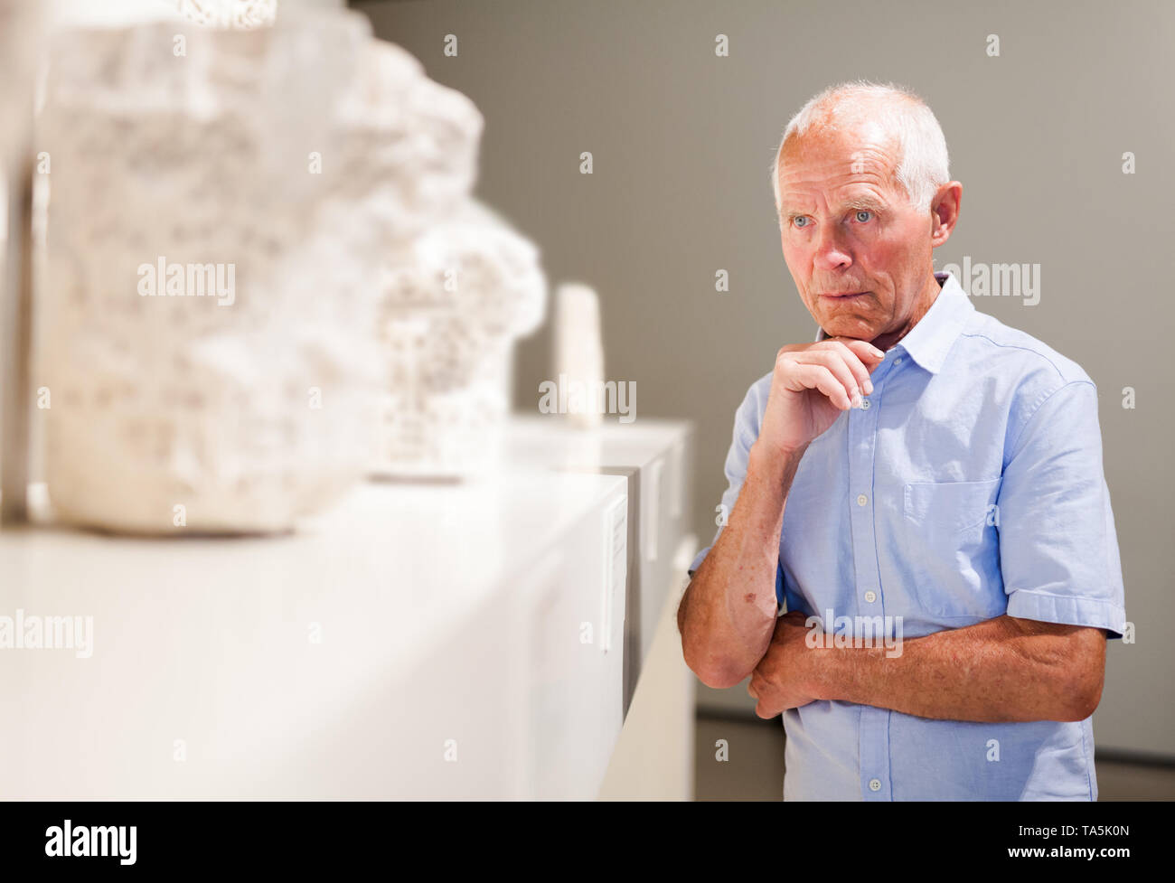 Attentive mature man observing sculptures exhibition in art museum ...