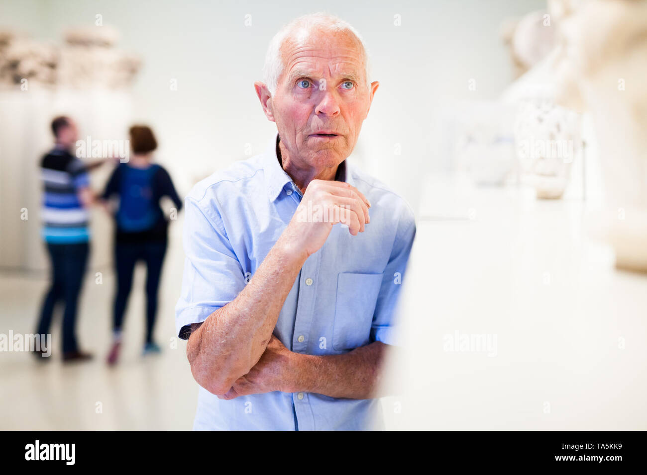 Attentive mature man observing sculptures exhibition in art museum ...