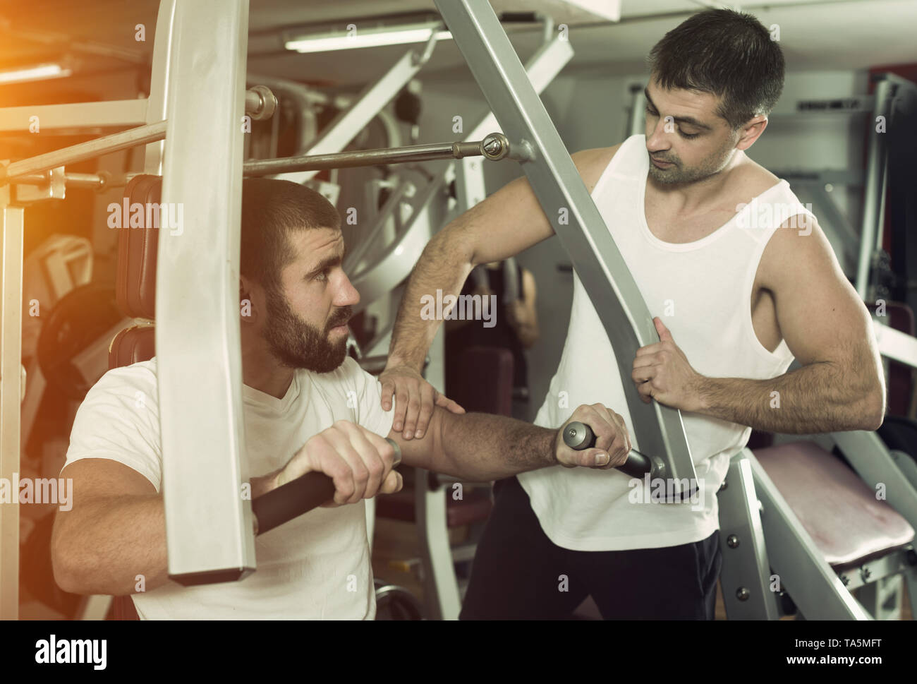 Male trainer explaining to muscular guy technique of performing ...