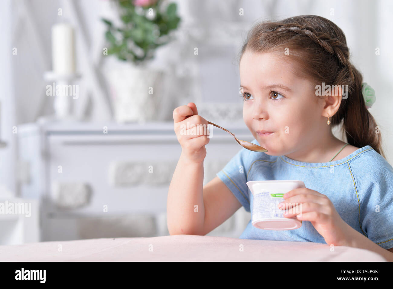 Portrait of cute little girl eating delicious yogurt Stock Photo - Alamy