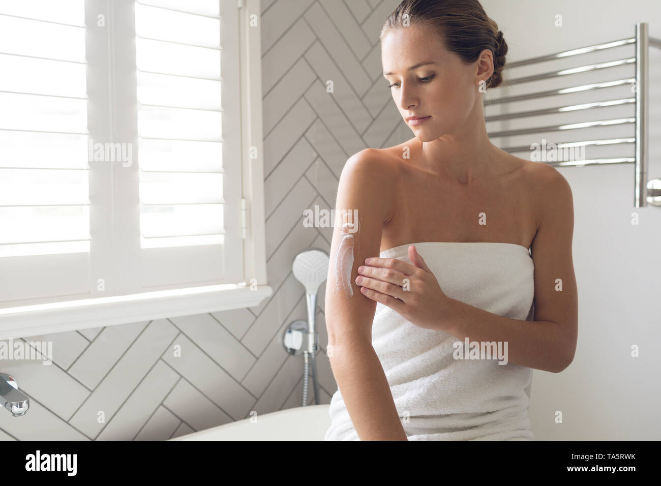 Beautiful woman applying lotion on her body in bathroom Stock Photo - Alamy