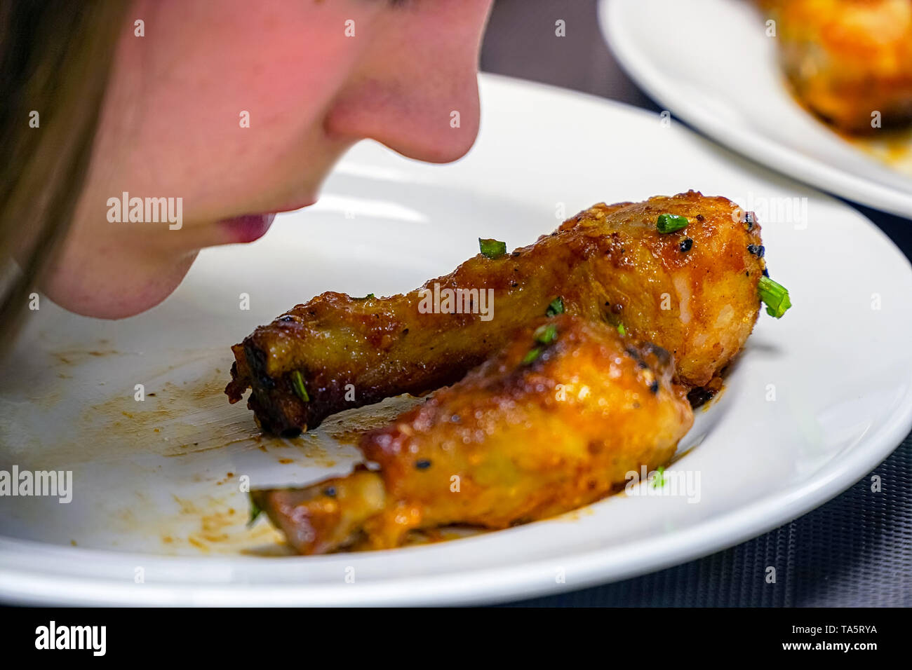 Girl sniffs fried chicken legs on plate Stock Photo - Alamy