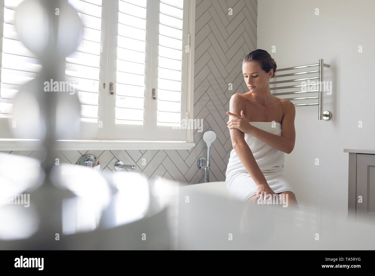 Beautiful woman applying lotion on her body in bathroom Stock Photo - Alamy