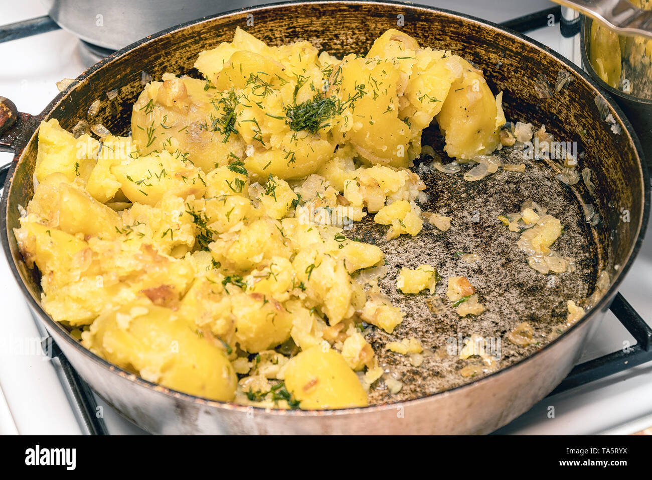 Fried potatoes with dill in a pan on gas stove Stock Photo - Alamy