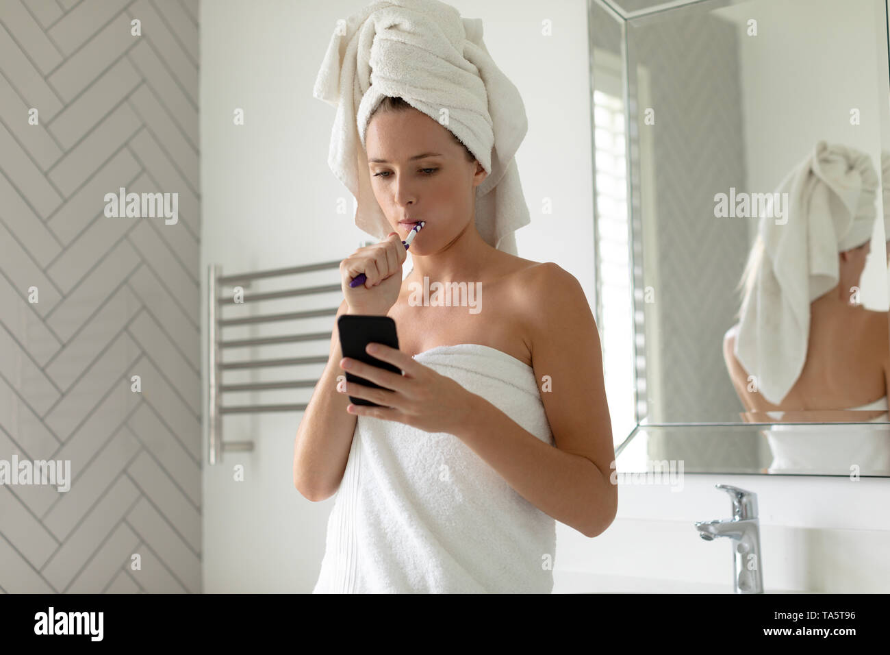 Beautiful woman using her phone while brushing her teeth Stock Photo ...