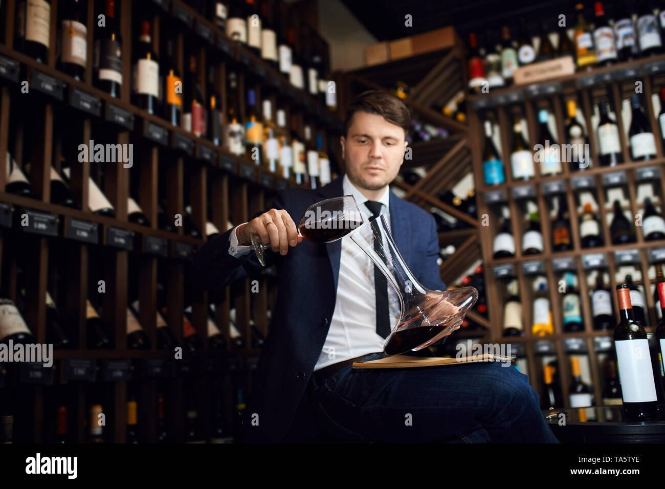elegant man pouring wine from glass to decanter. close up photo. the ...