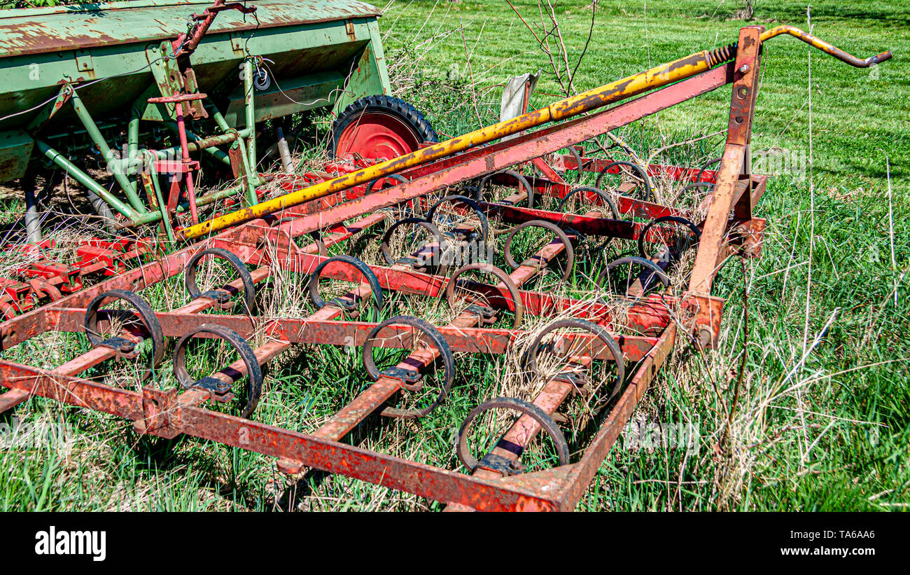 Old, rusty and abandoned red agricultural cultivator next to an old ...