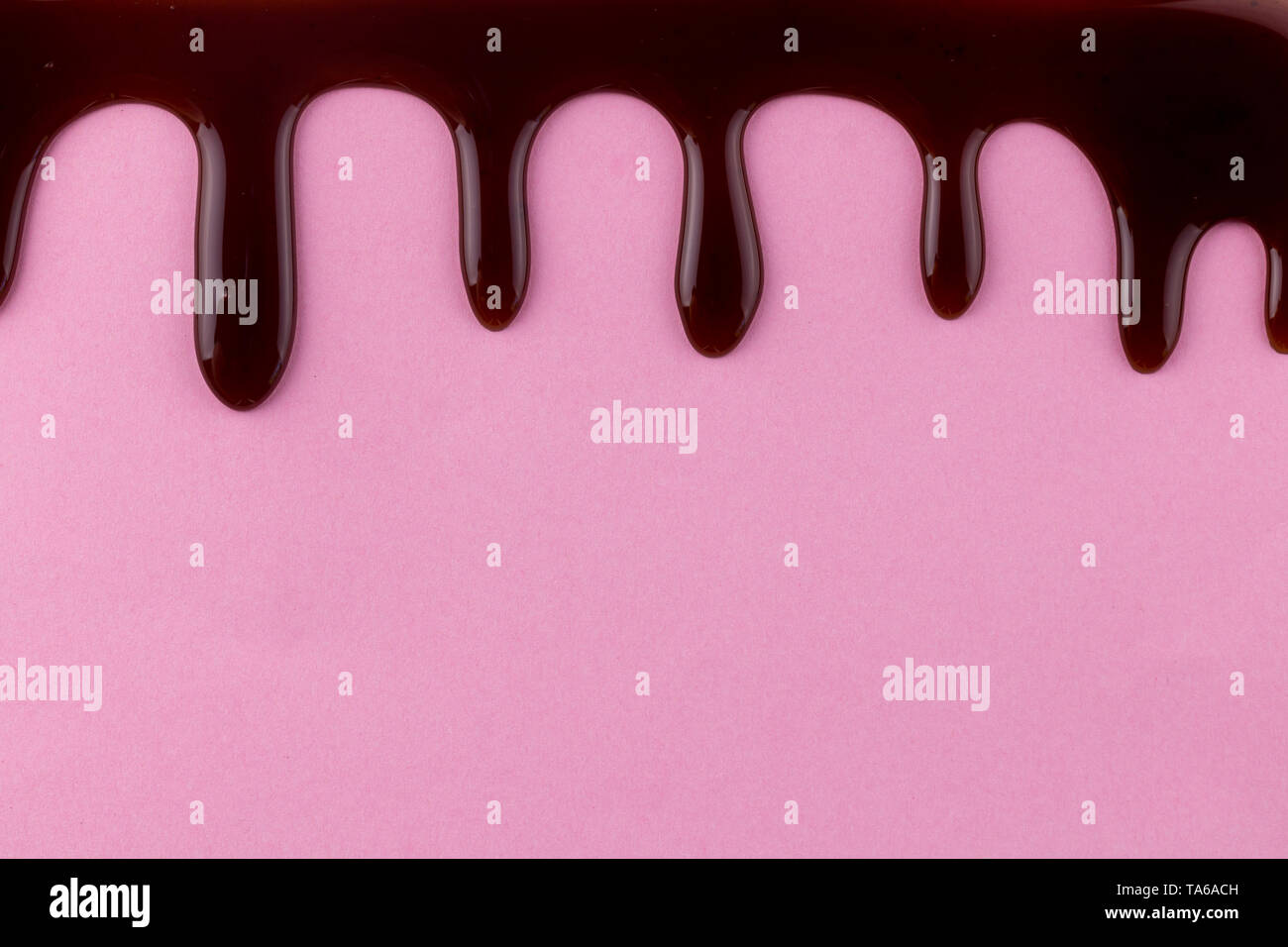 Cake topping chocolate flowing downwards in drooping way on pink ...