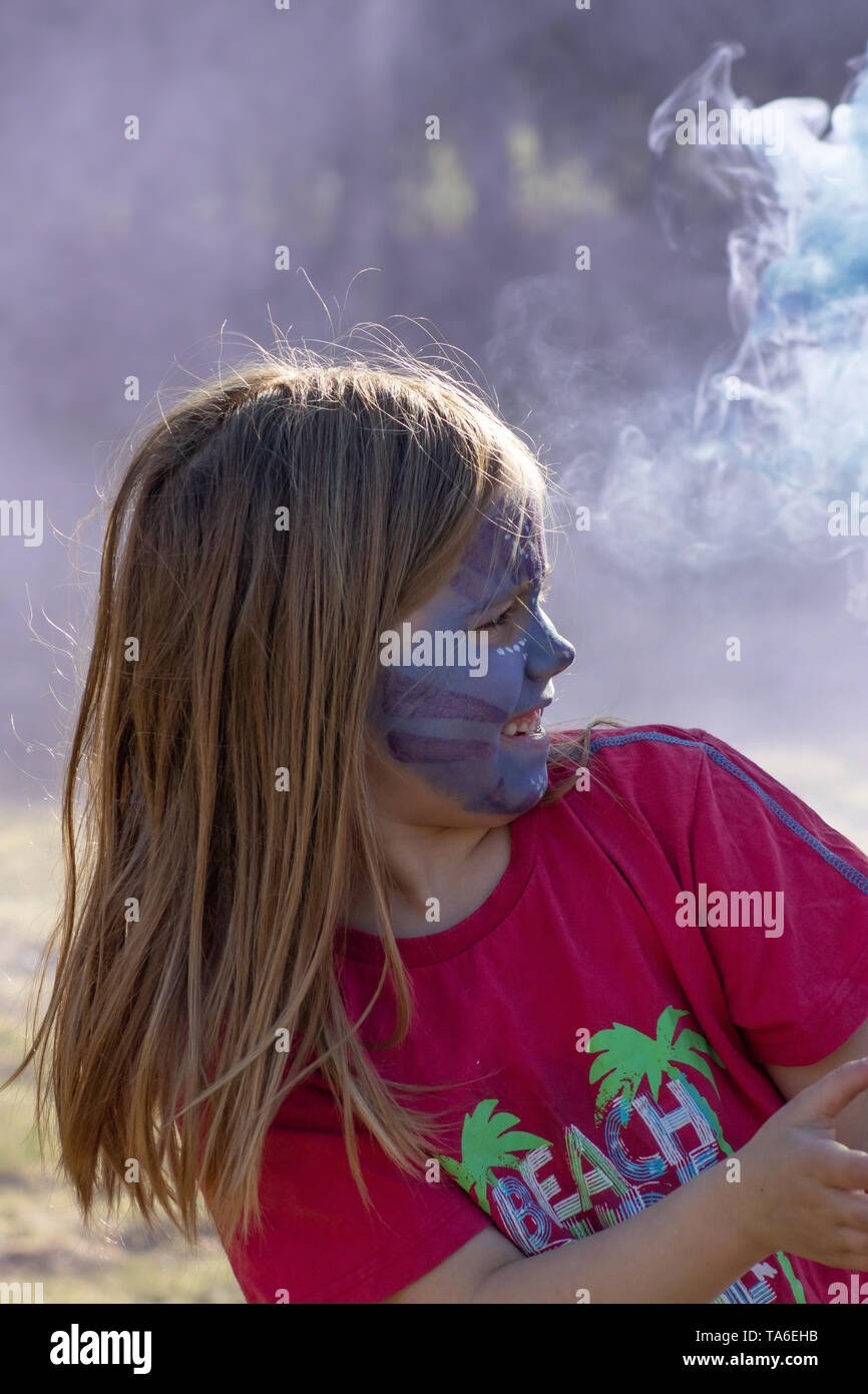 Girl with face paint holding smoke bomb Stock Photo - Alamy