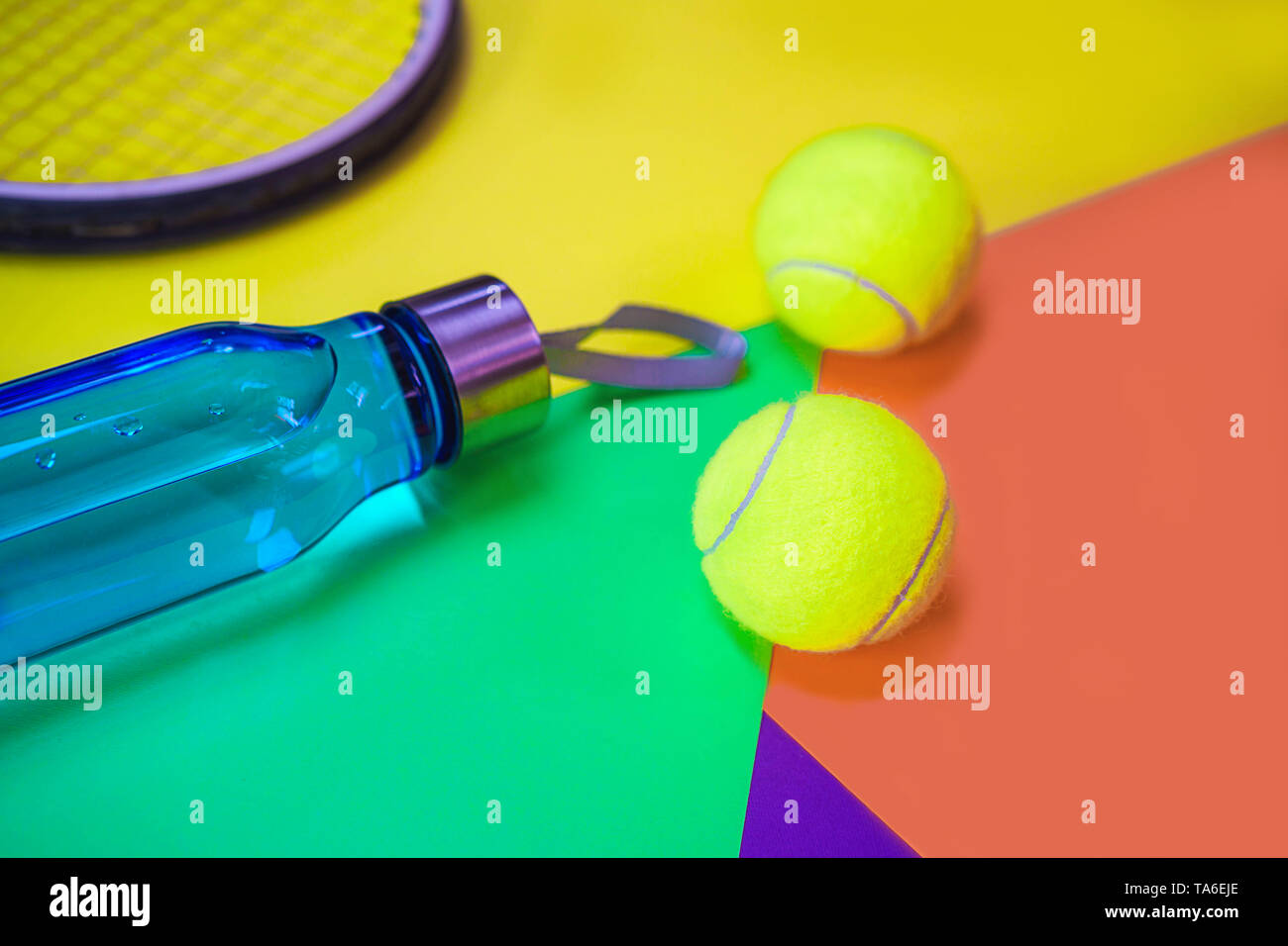 Tennis layout with tennis balls, racket, bottle of water on abstract ...