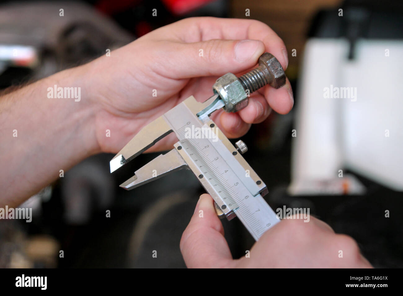 Worker with tools in hands. Mechanic is checking and measuring screw ...