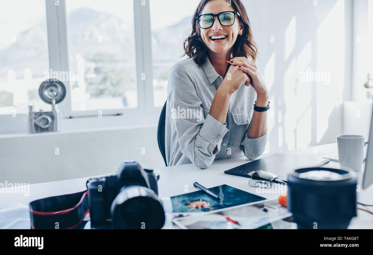 Female photo editor sitting at her desk. Female photographer looking at ...