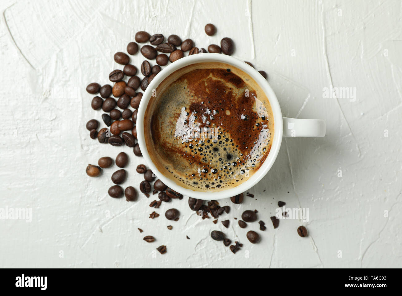 Cup of coffee with frothy foam and coffee beans on white background ...