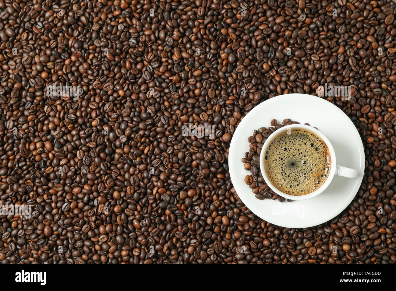 Cup of coffee with frothy foam on beans background, top view and space ...