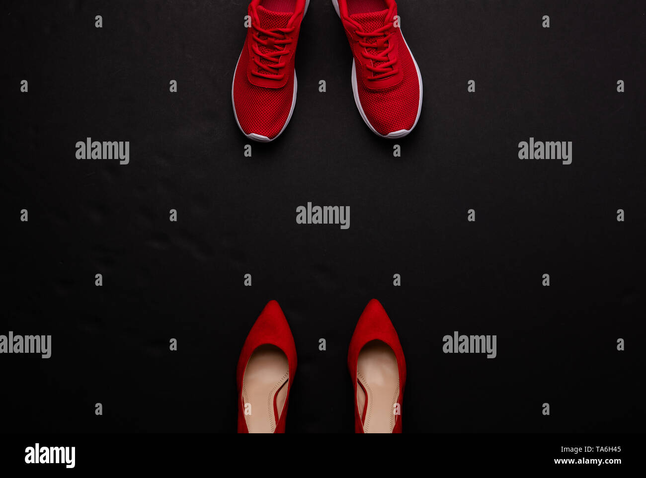 A studio shot of pair of running vs high heel shoes on black background ...