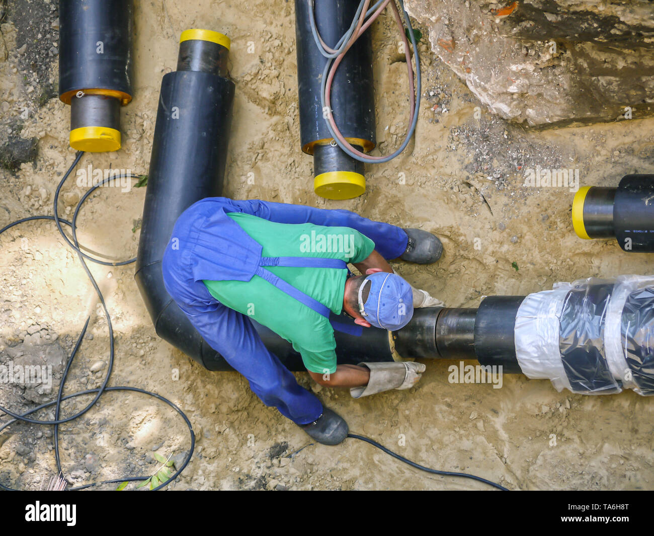 Welder welding heating installation pipes in the trench Stock Photo - Alamy