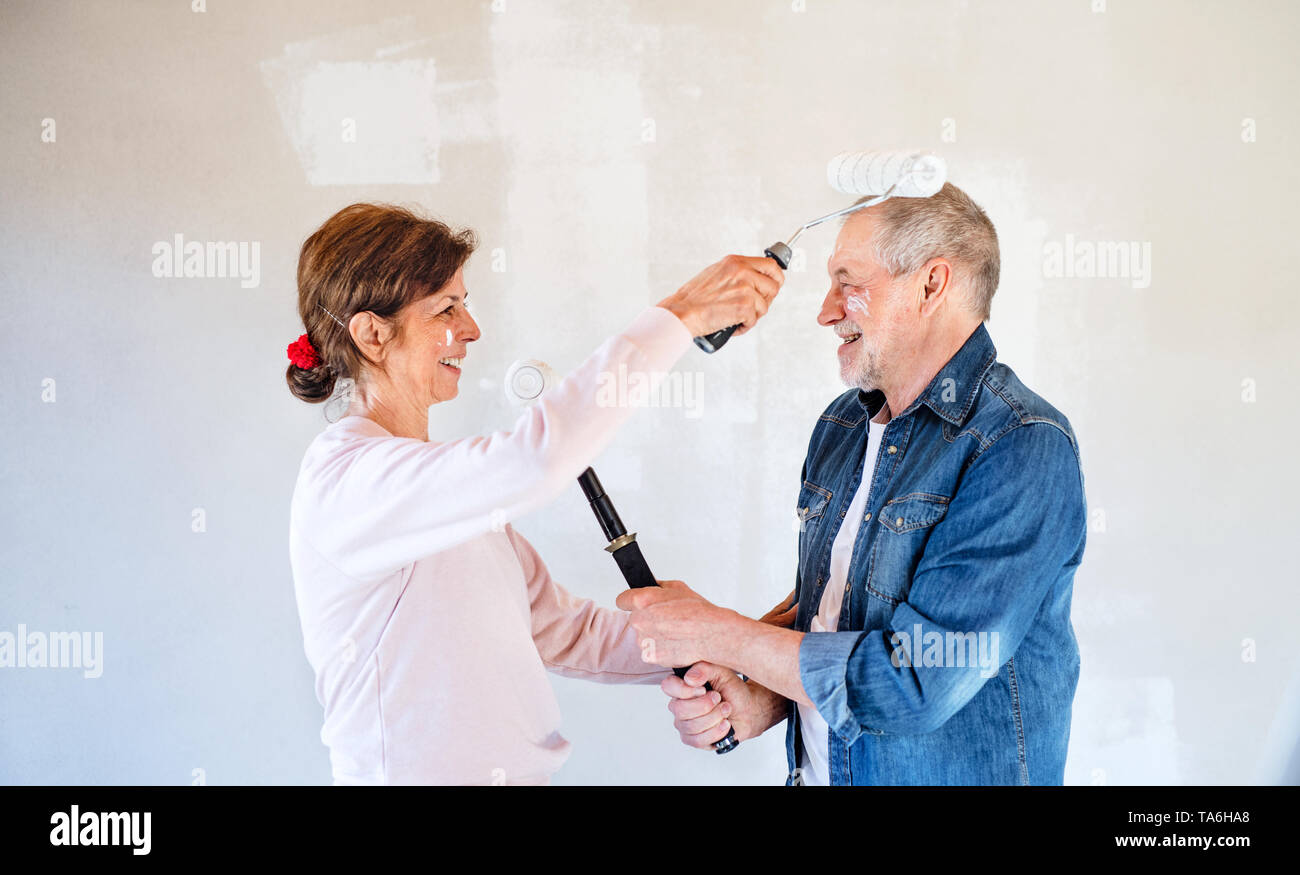 Senior couple painting walls in new home, having fun. Relocation ...