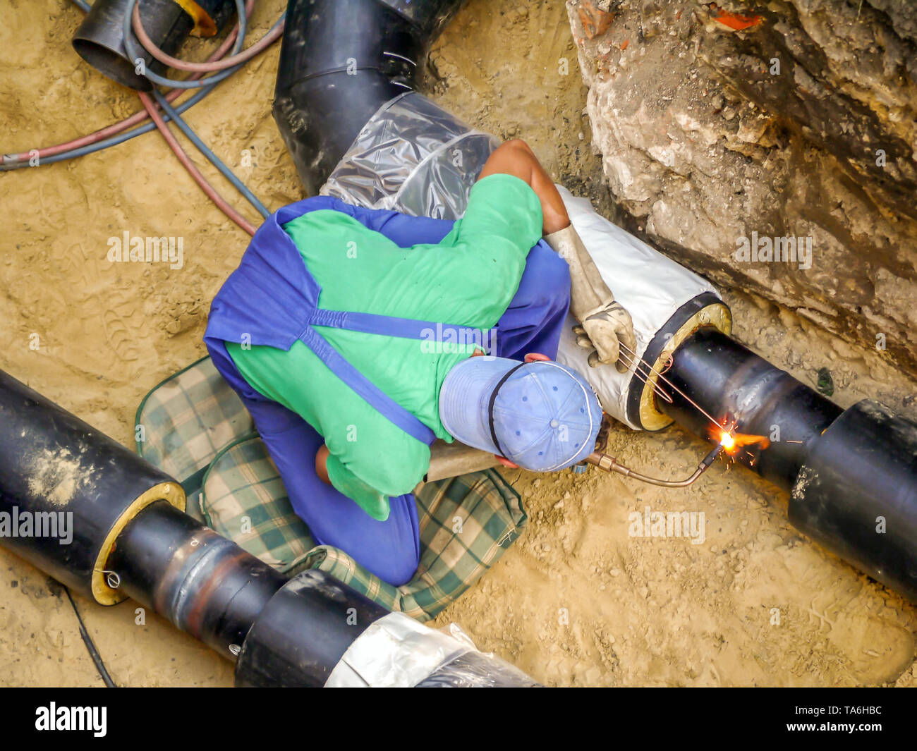 Welder welding heating installation pipes in the trench Stock Photo - Alamy