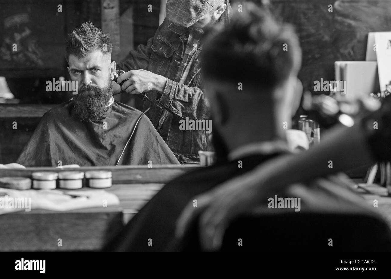 Barber with clipper trimming hair on nape of client. Reflexion of ...