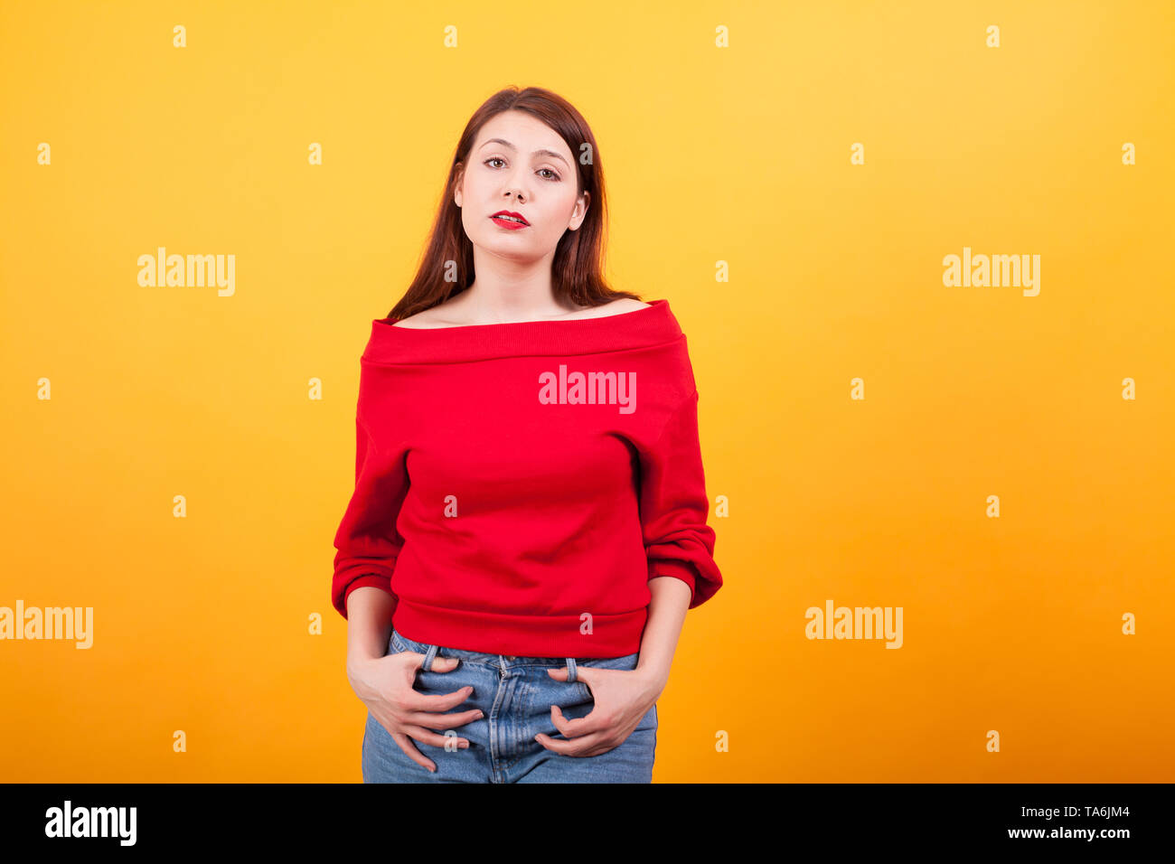 Portrait of attractive disappointed young woman over yellow background ...
