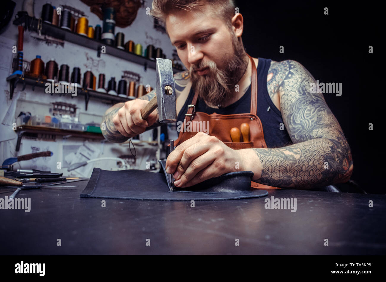 Leather Currier cutting out leather shapes for a new product in his ...
