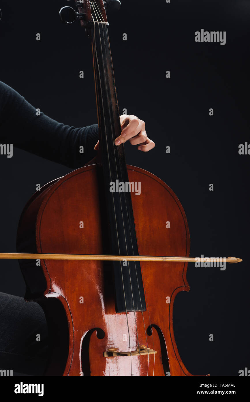 cropped view of woman playing double bass in darkness isolated on black ...