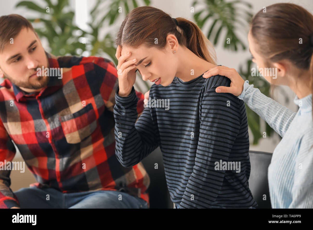Group of people calming their friend indoors Stock Photo - Alamy