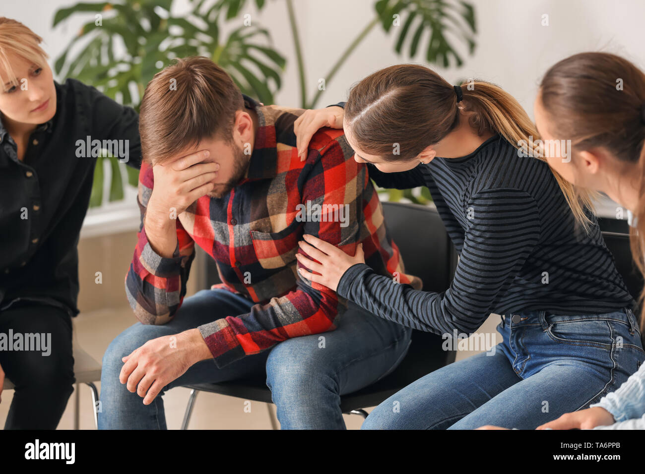 Group of people calming their friend indoors Stock Photo - Alamy