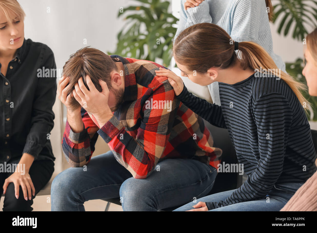 Group of people calming their friend indoors Stock Photo - Alamy