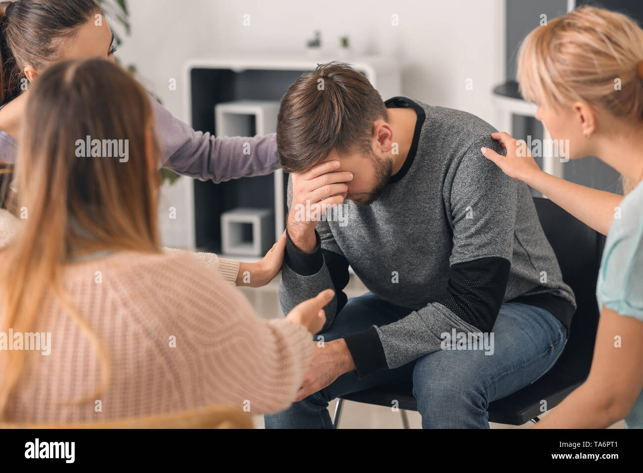 Group of people calming their friend indoors Stock Photo - Alamy