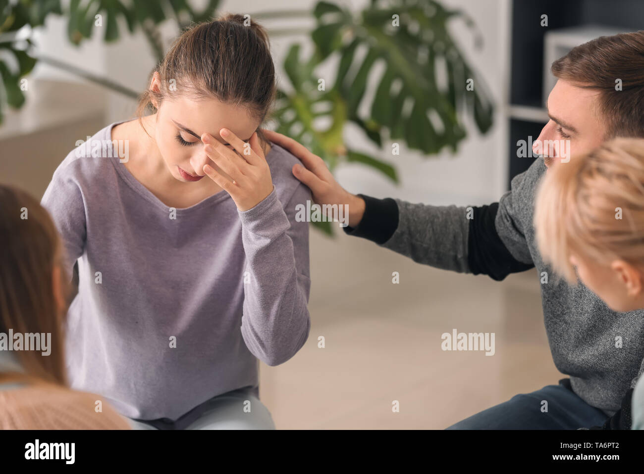Group of people calming their friend indoors Stock Photo - Alamy