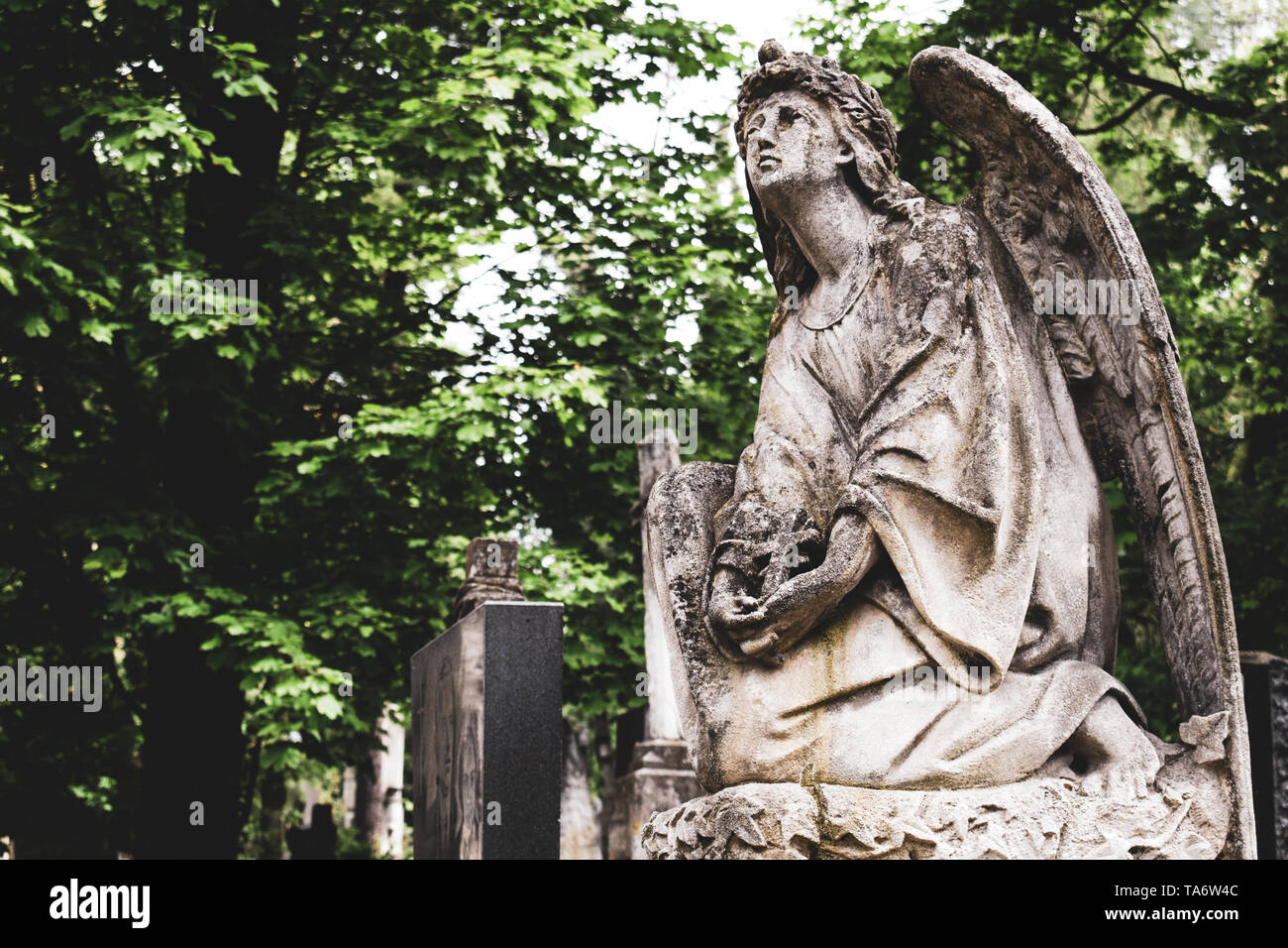 Obsolete old stature of angel with cross on burial on cemetery in ...