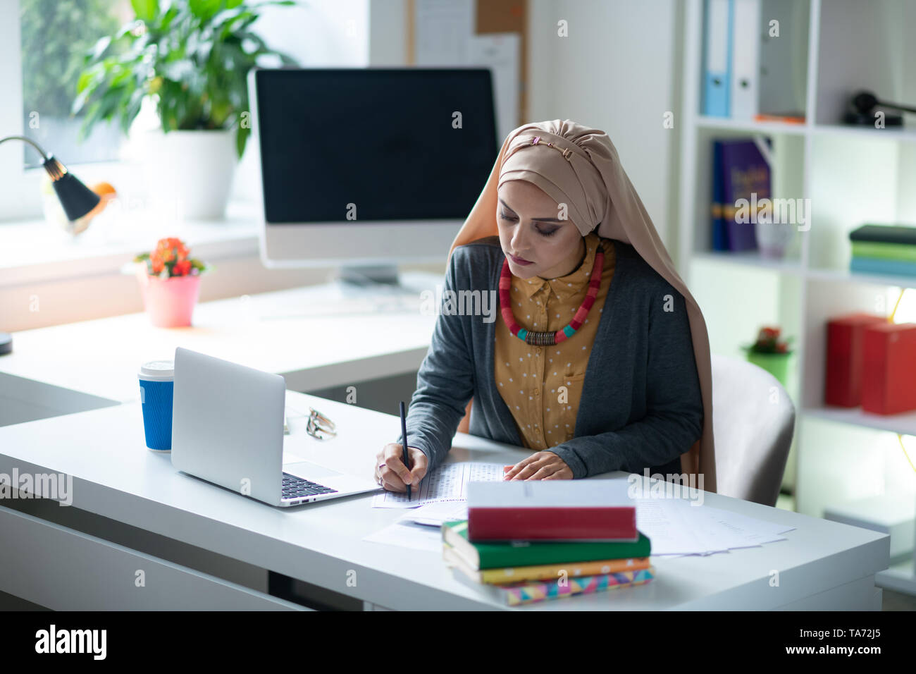 Busy teacher sitting at the table and preparing lesson Stock Photo - Alamy