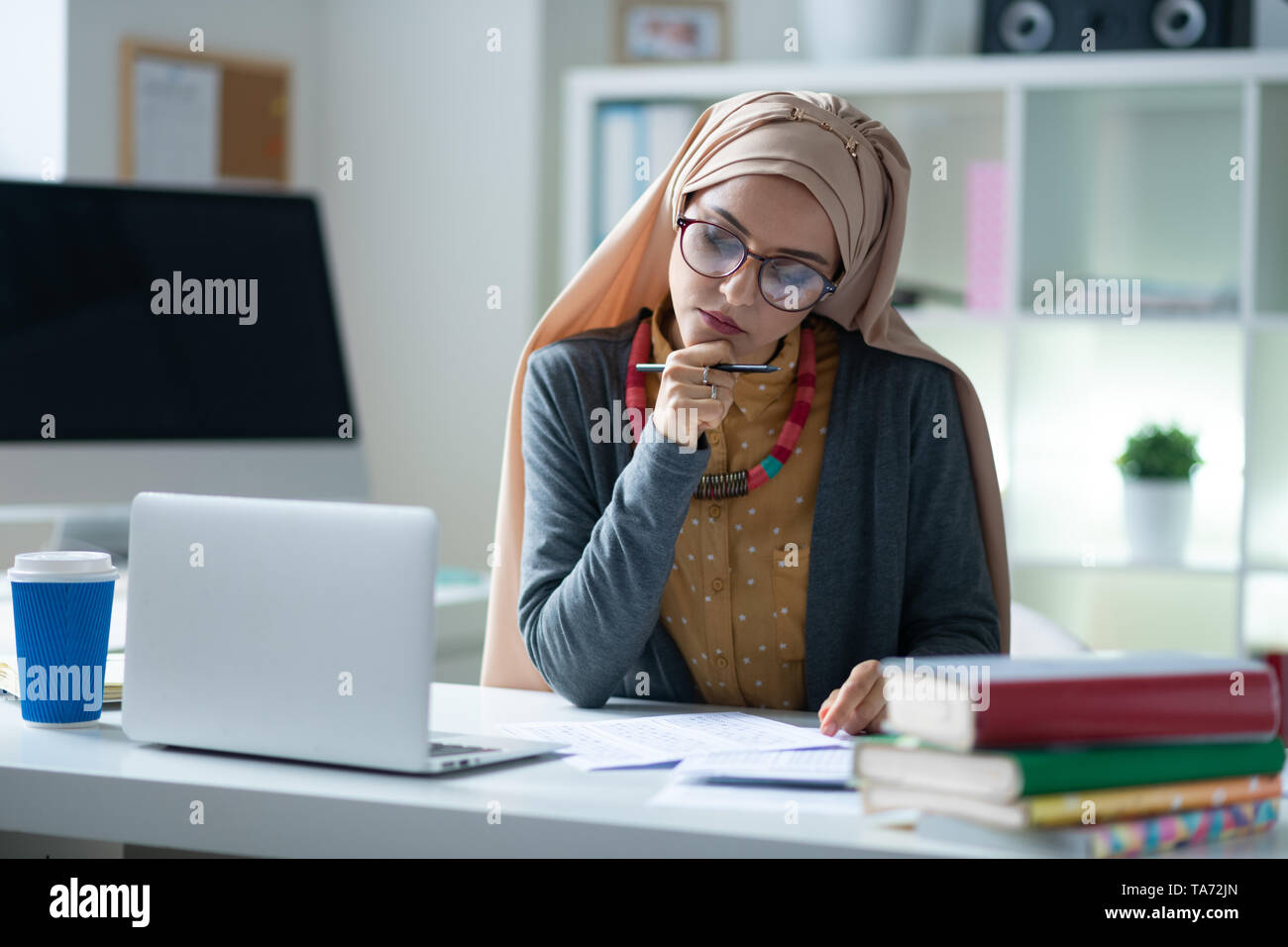 Teacher wearing glasses holding pen correcting tests Stock Photo - Alamy