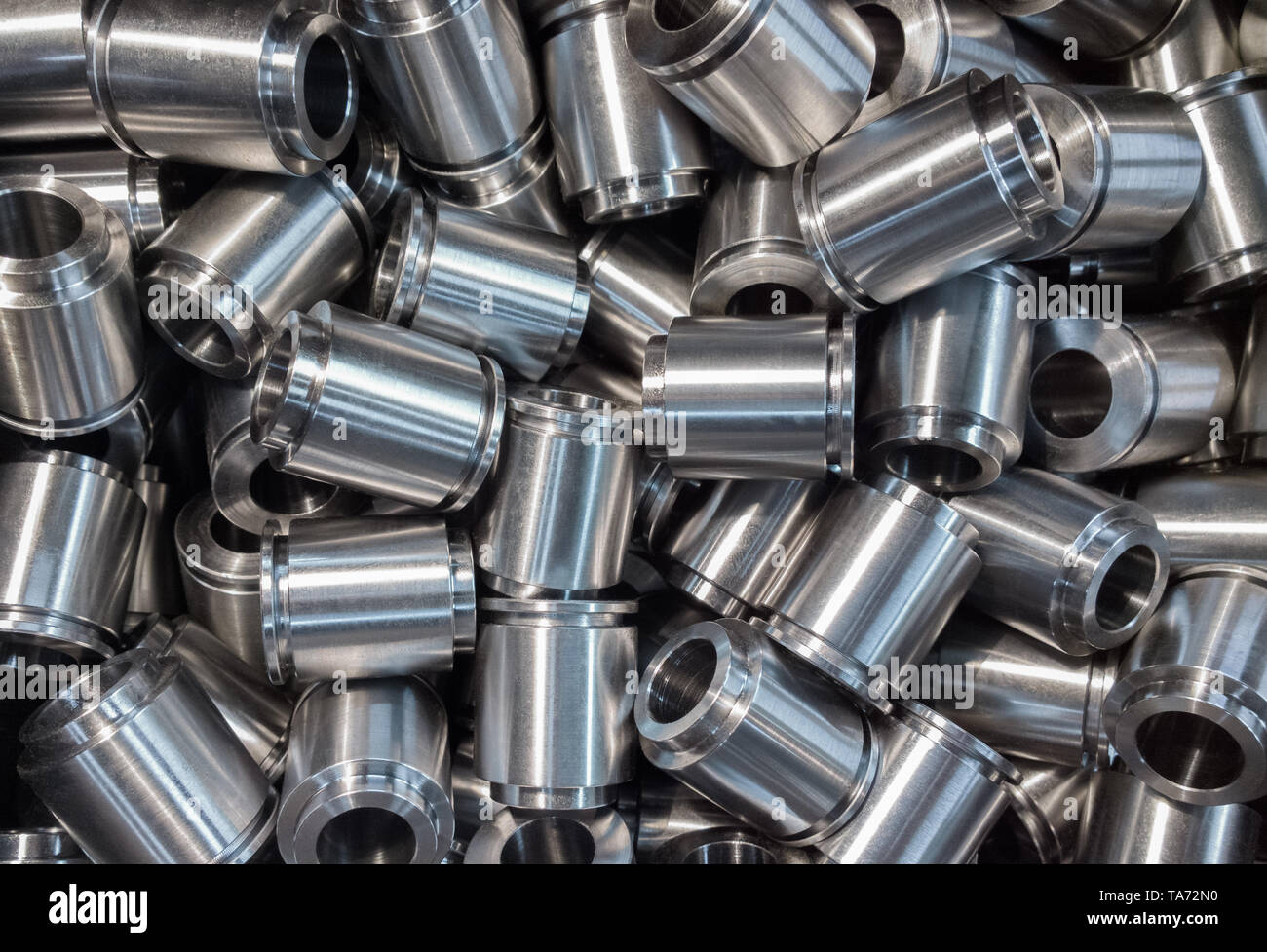 A lot of small equal shiny steel parts flat background. Raw metal ...