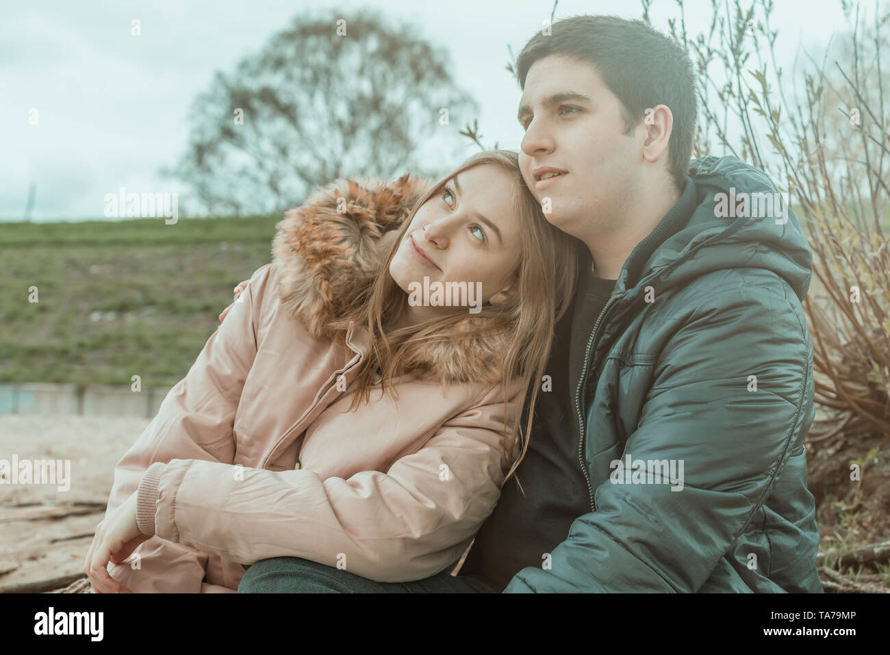A young couple sitting happily together in nature Stock Photo - Alamy