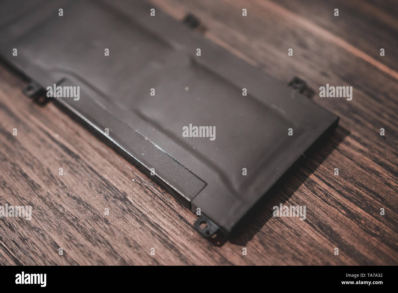 Swollen Lithium Polymer (Li-Po) laptop battery on a wooden table. Known ...