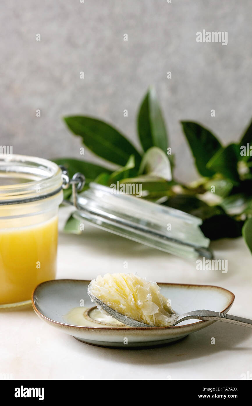 Homemade Melted ghee clarified butter in open glass jar and spoon on ...