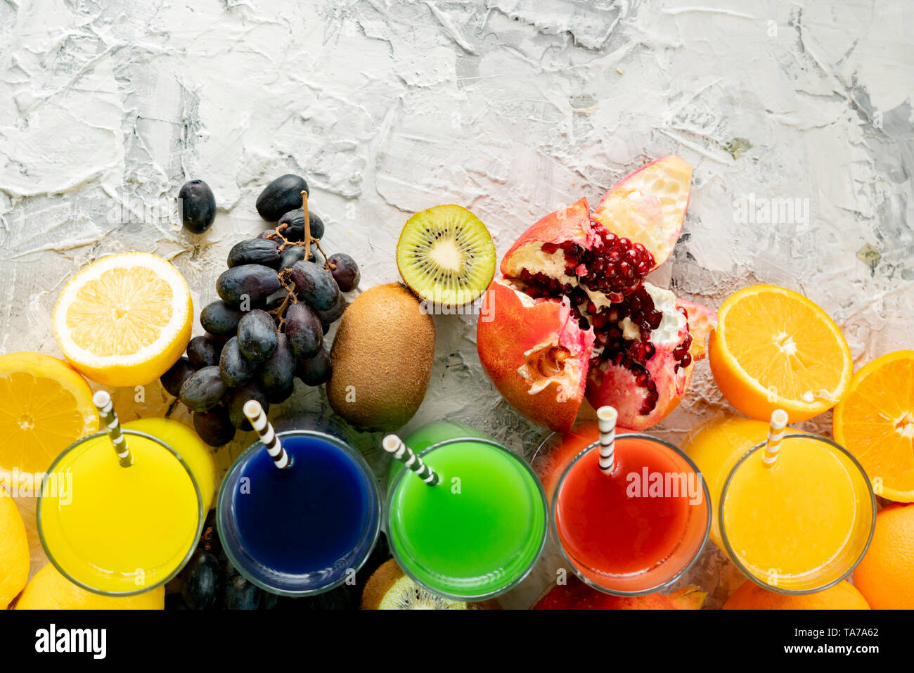 top view of fresh juice variety, different fruits around, copy space ...
