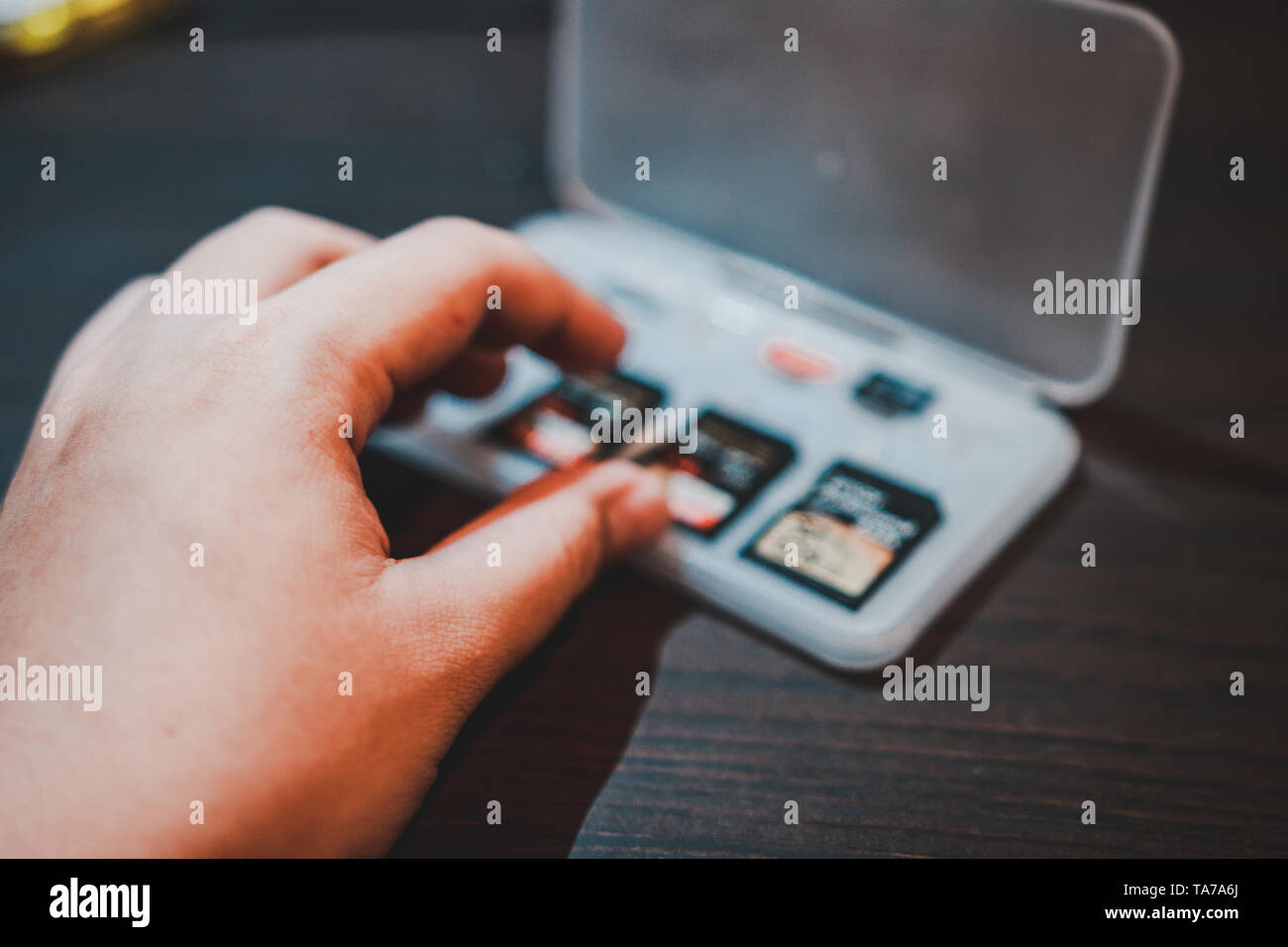 Hand picking SD card in a plastic storage box on the wooden table to be ...