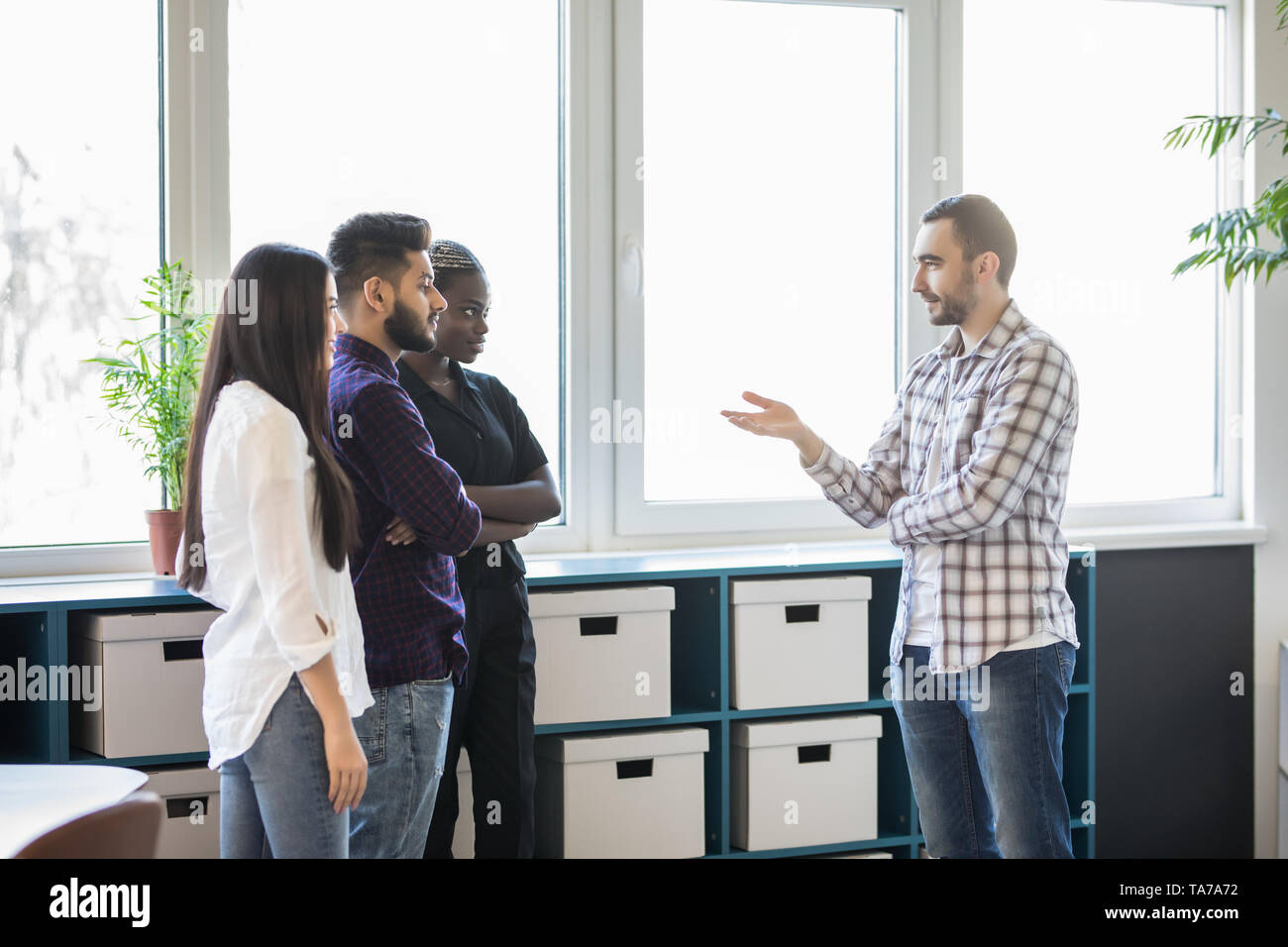 Informal meeting of team standing at break in modern office Stock Photo ...