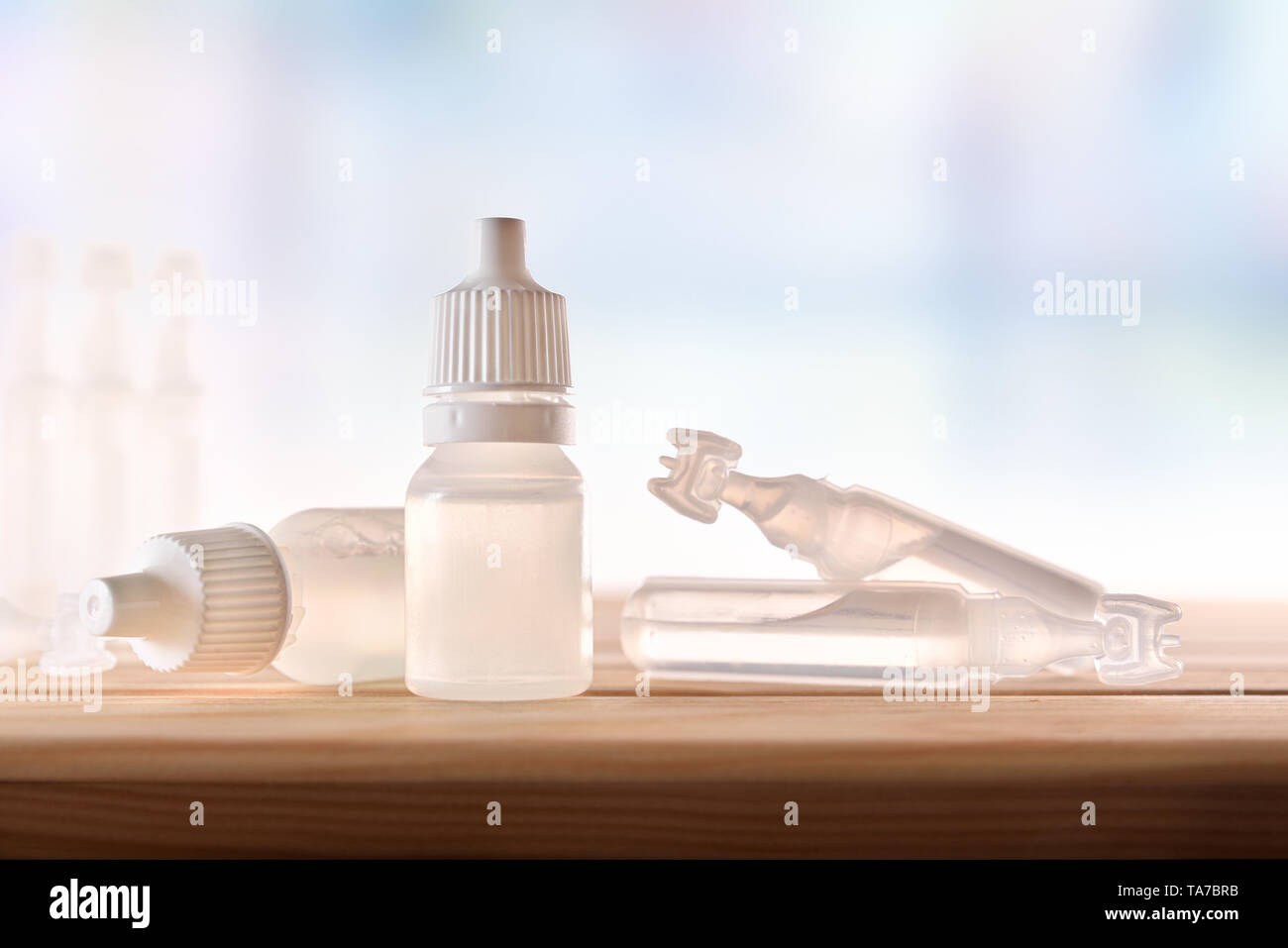 Plastic bottle with eye medication on wooden table in room. Horizontal ...
