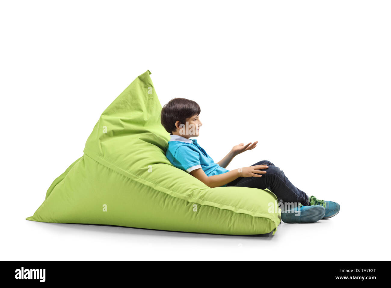 Full length profile shot of a boy sitting on a green bean bag and ...